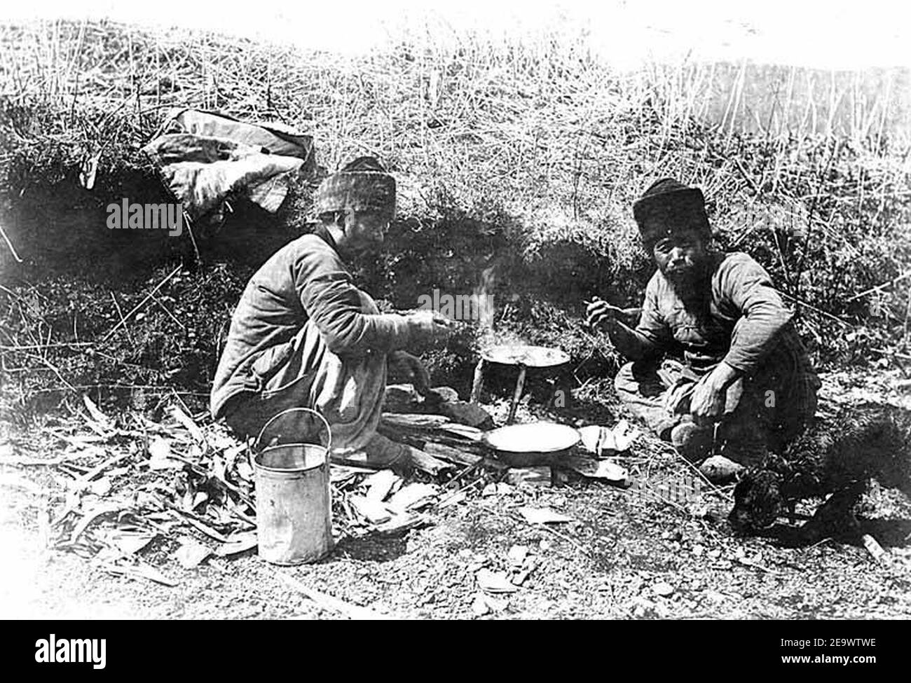 Native men, possibly Siberian Eskimos, eating meal prepared over fire ...