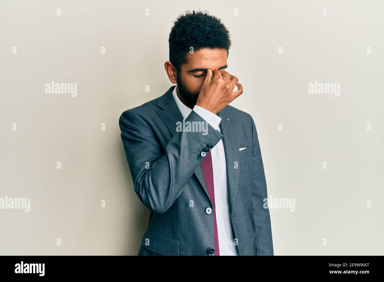 Handsome hispanic man with beard wearing business suit and tie tired ...