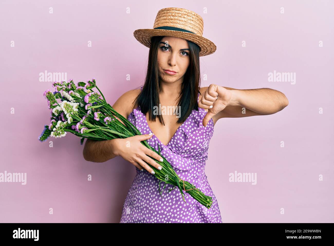 Young brunette woman wearing summer dress holding bouquet of flowers ...