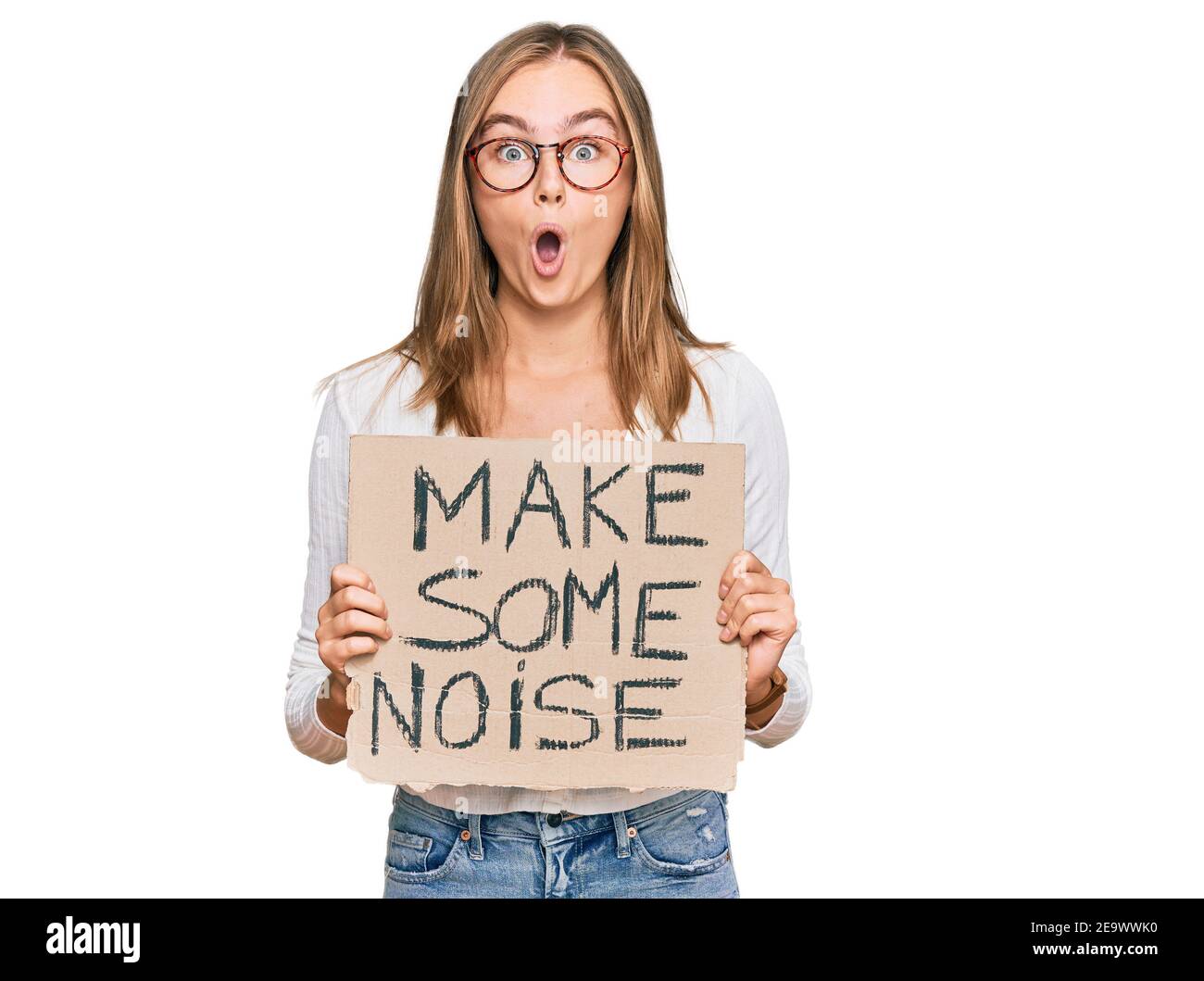 Beautiful blonde woman holding make some noise banner scared and amazed ...