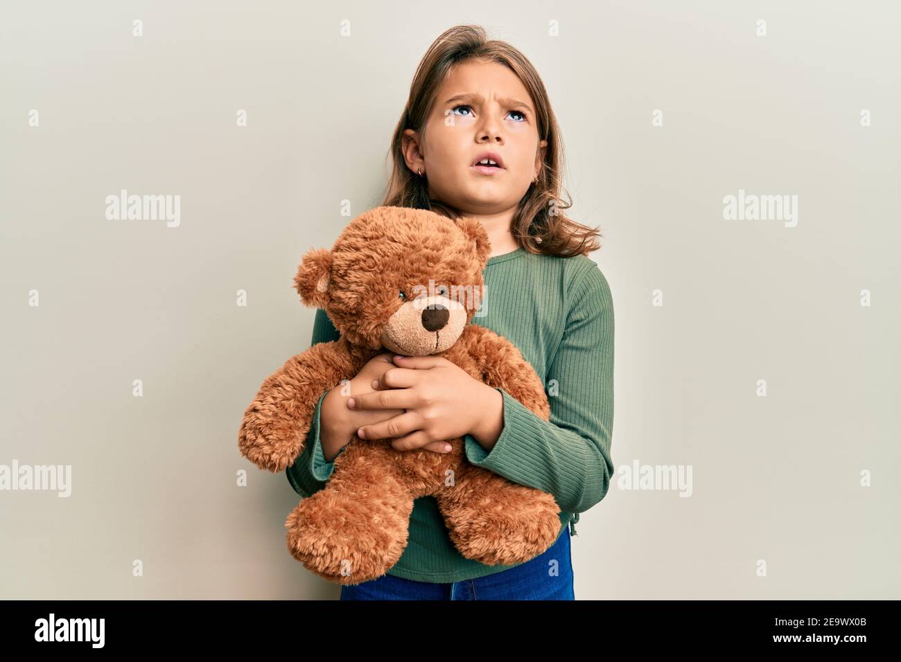 Little beautiful girl hugging teddy bear angry and mad screaming ...