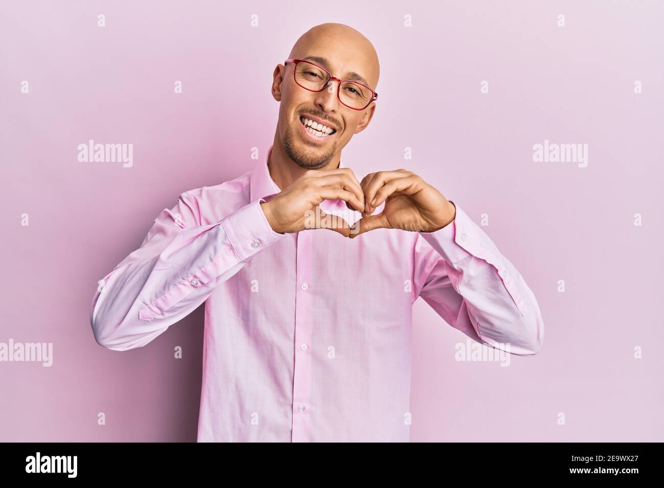 Bald man with beard wearing casual clothes and glasses smiling in love ...