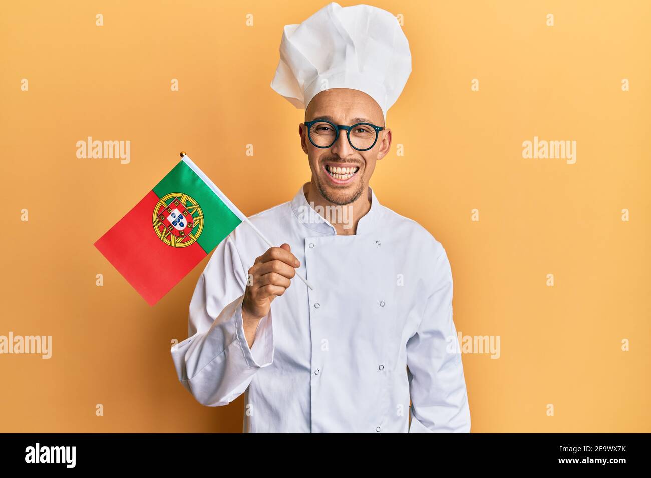 Bald man with beard wearing professional cook apron holding portugal ...