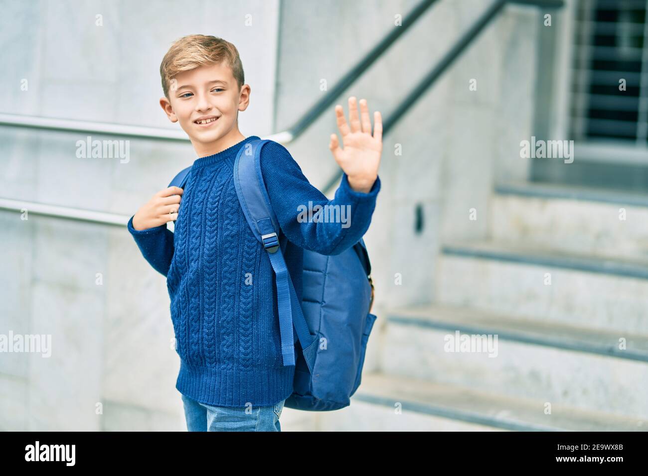Adorable blond student kid saying goodbye with hand getting in the ...