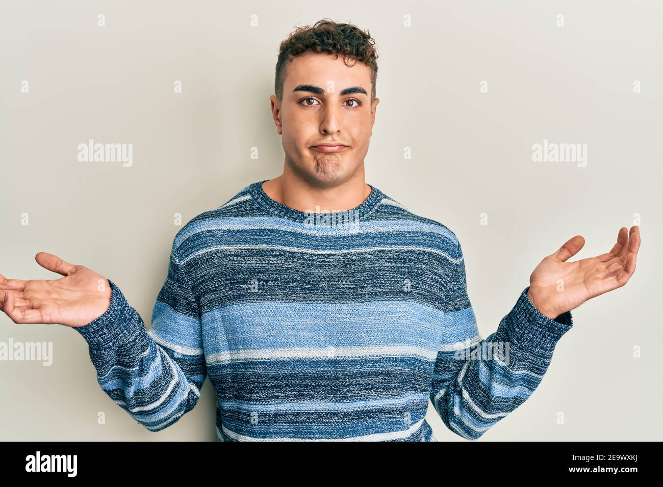 Hispanic young man wearing casual winter sweater clueless and confused ...