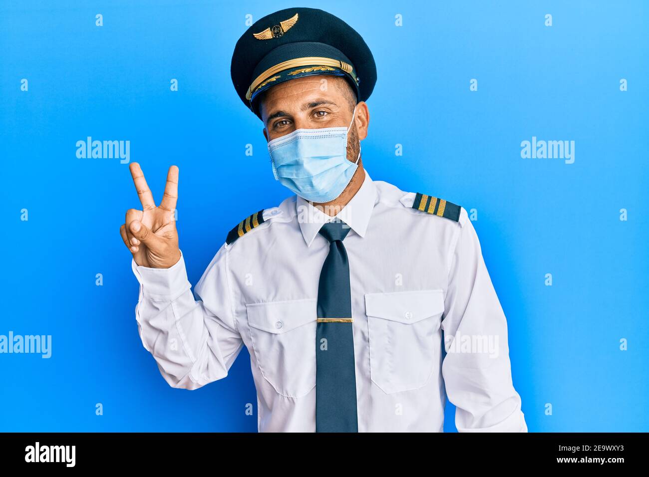 Handsome man with beard wearing airplane pilot uniform wearing safety ...
