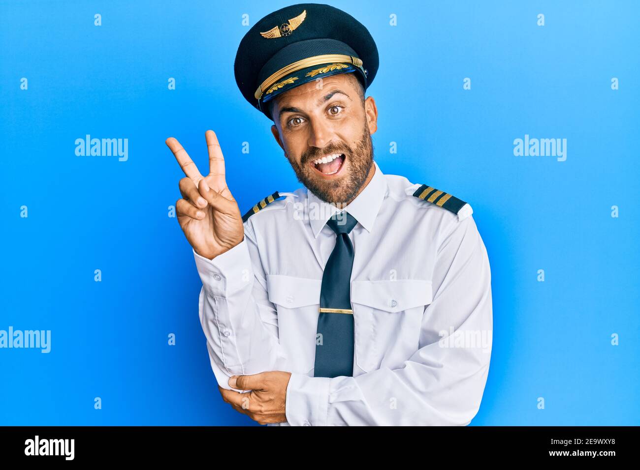 Handsome man with beard wearing airplane pilot uniform smiling with ...