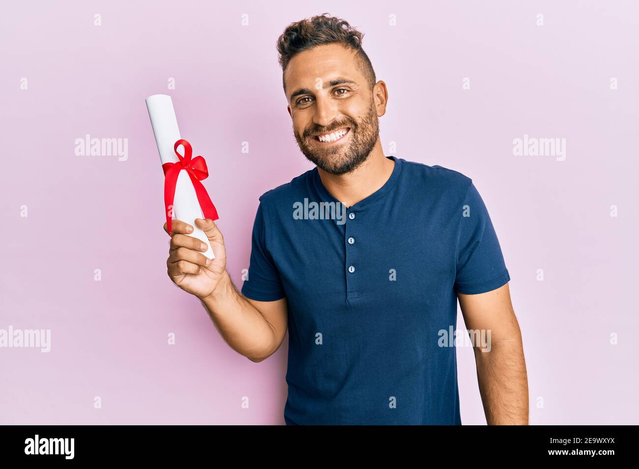 Handsome man with beard holding graduate degree diploma looking ...