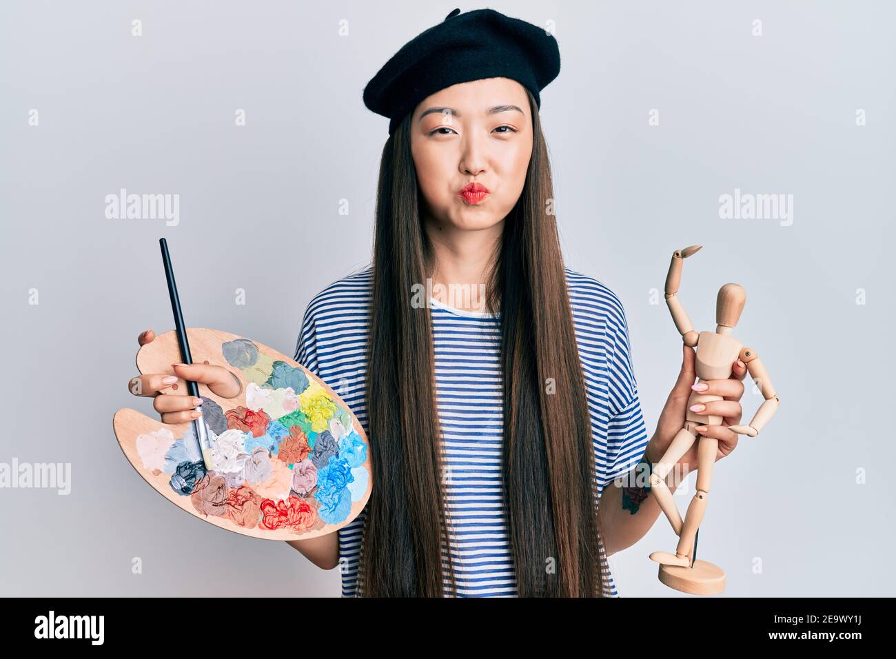 Young chinese woman wearing artist look with beret holding manikin ...