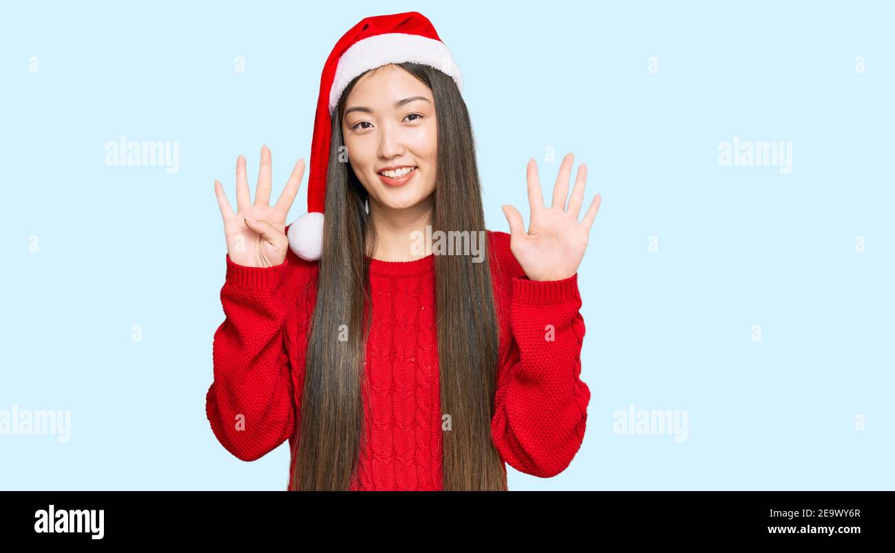 Young chinese woman wearing christmas hat showing and pointing up with ...