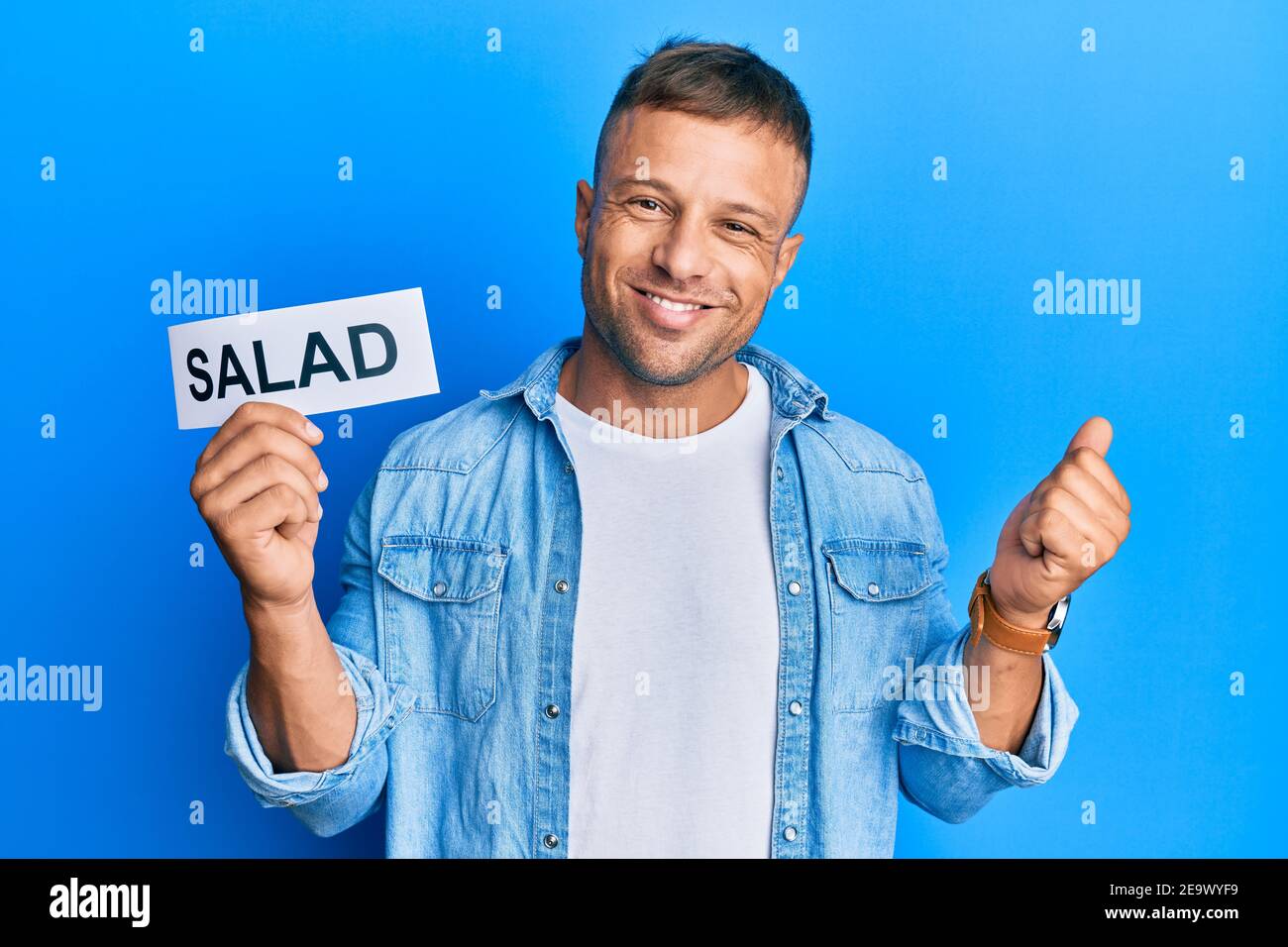 Handsome muscle man holding salad word on paper screaming proud ...