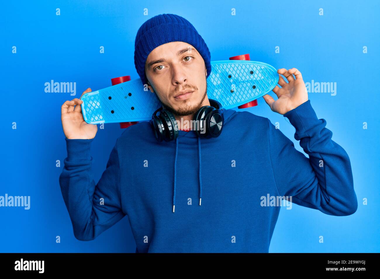 Hispanic young man holding skate relaxed with serious expression on ...