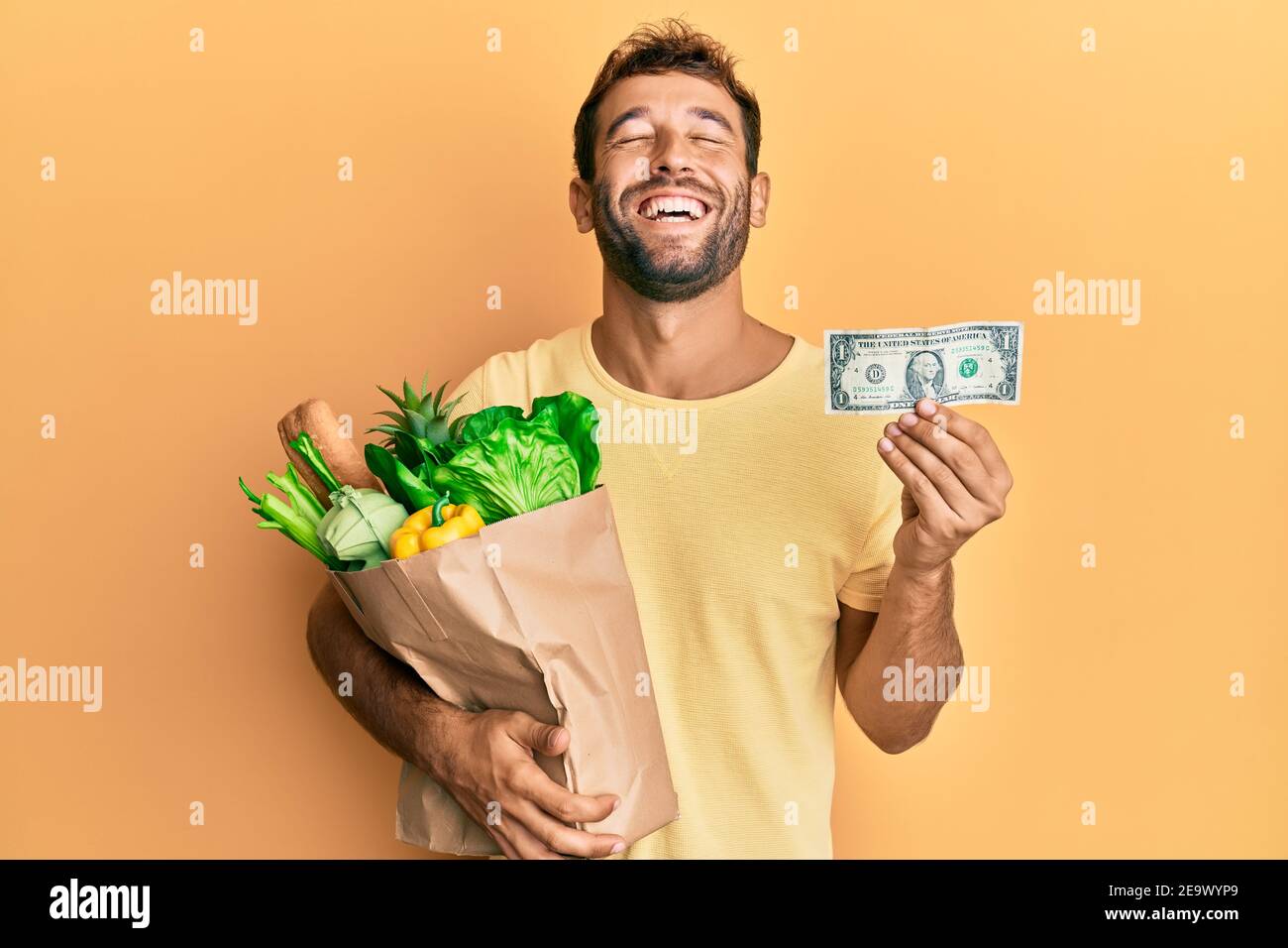Handsome man with beard holding groceries and 1 american dollar ...