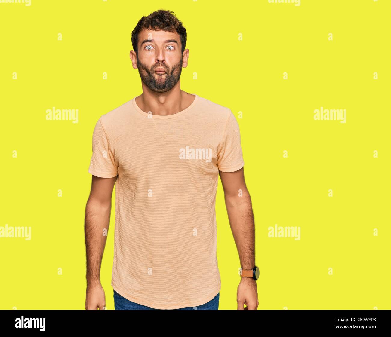 Handsome young man with beard wearing casual tshirt making fish face ...
