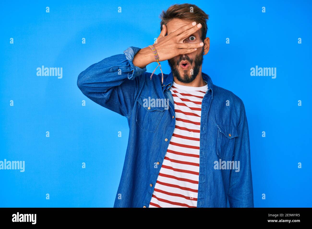 Handsome caucasian man with beard wearing casual clothes peeking in ...