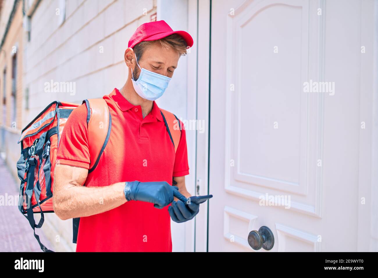 Caucasian delivery man wearing red uniform and delivery backpack and ...