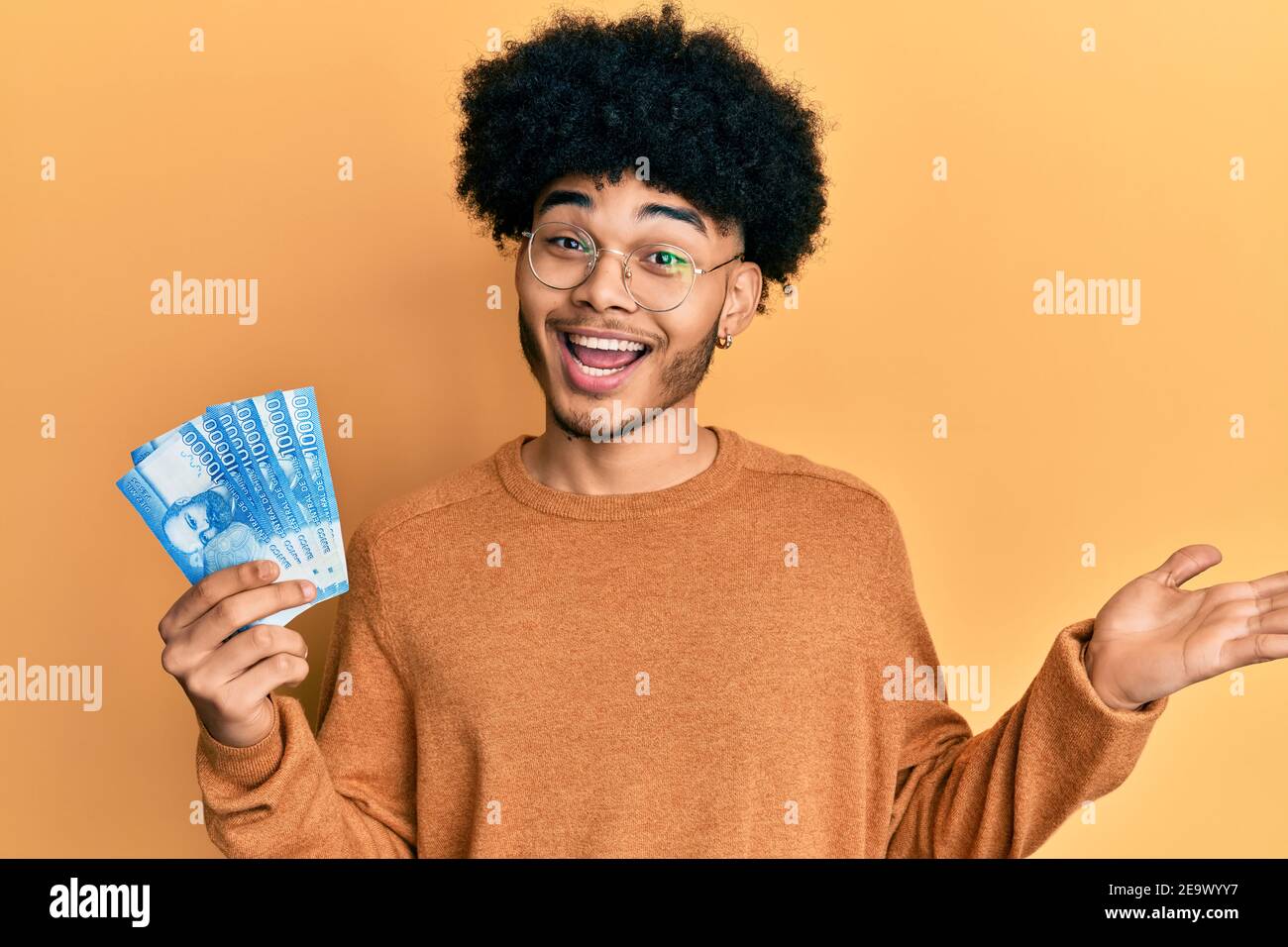 Young african american man with afro hair holding 10000 chilean pesos ...