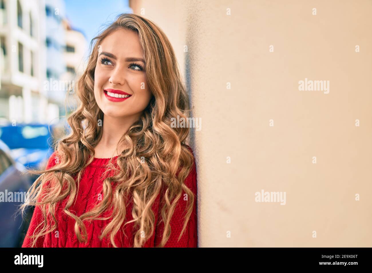 Young blonde girl smiling happy leaning on the wall at the city Stock ...