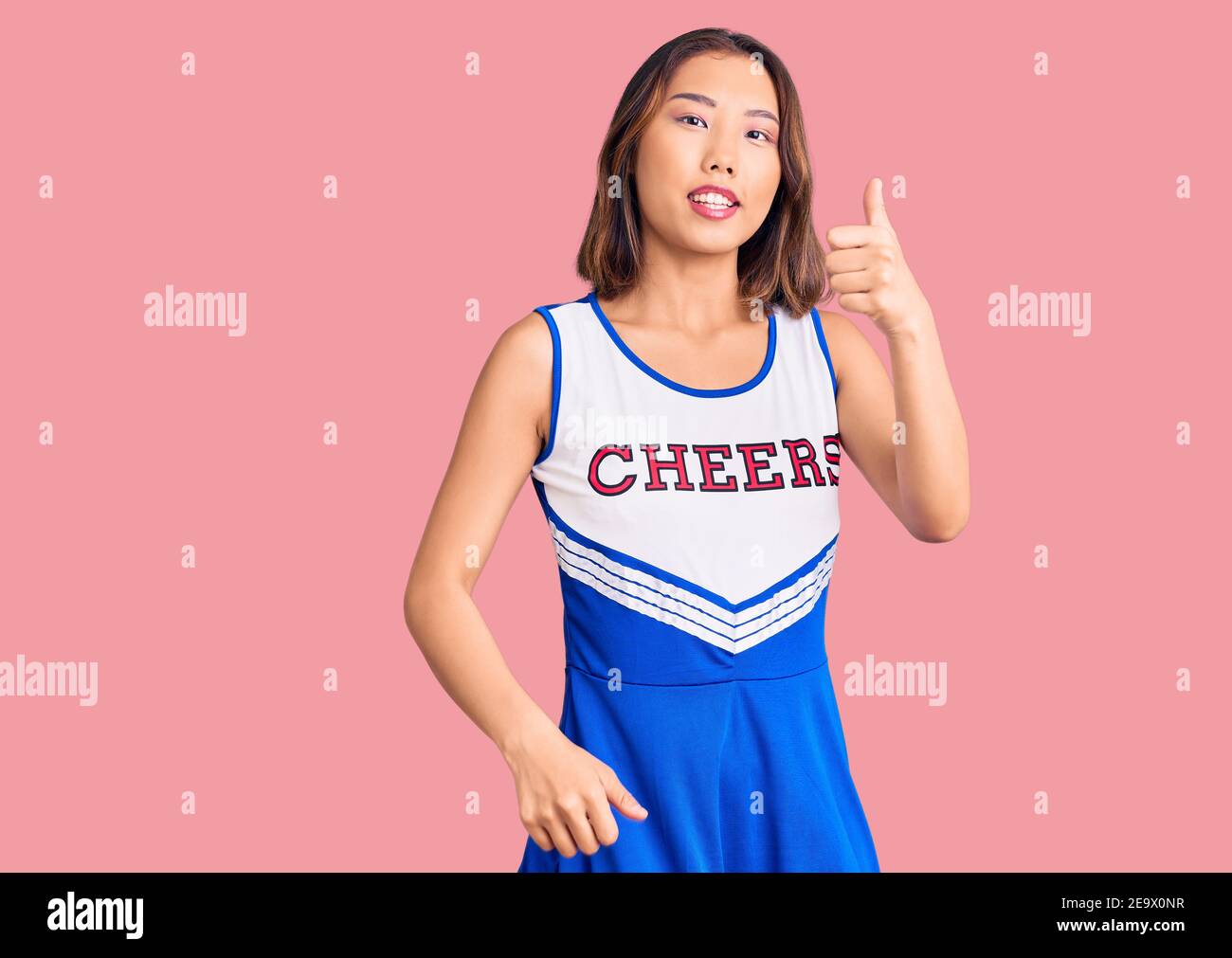 Young beautiful chinese girl wearing cheerleader uniform doing happy ...