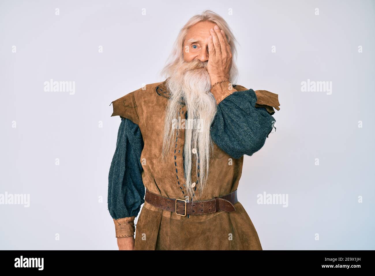 Old senior man with grey hair and long beard wearing viking traditional ...