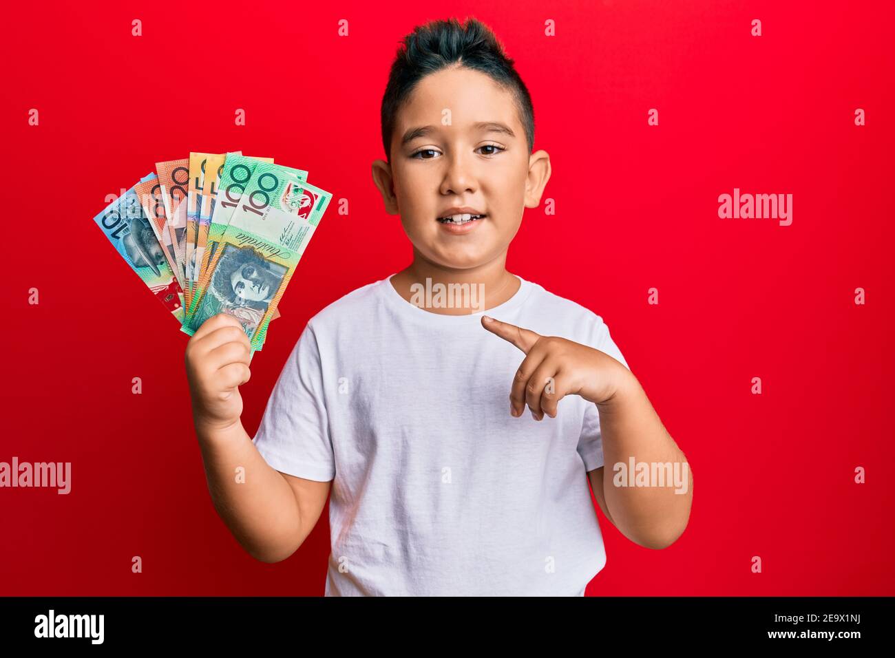 Little boy hispanic kid holding australian dollars smiling happy ...