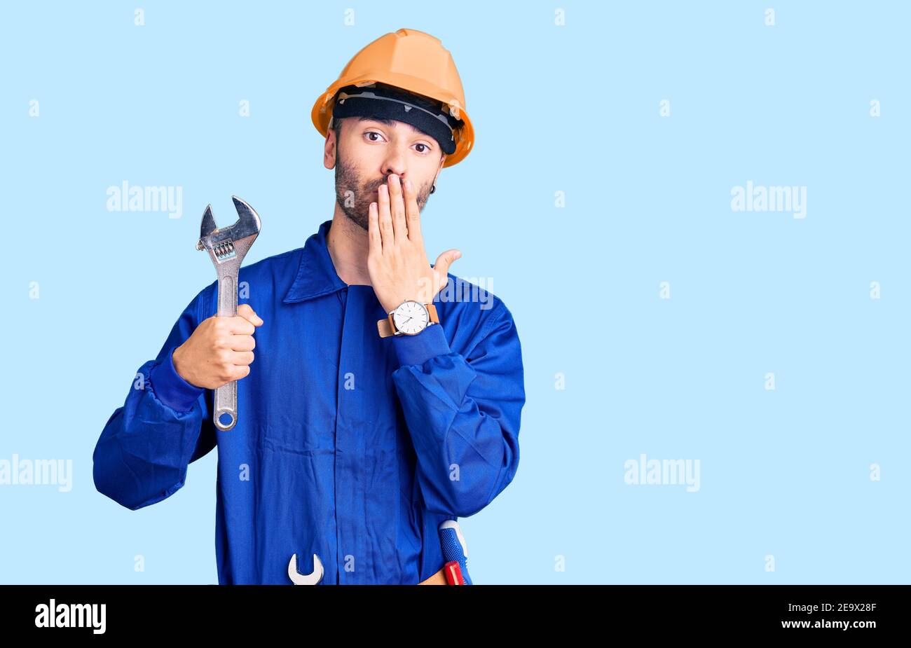 Young hispanic man wearing electrician uniform holding wrench covering ...