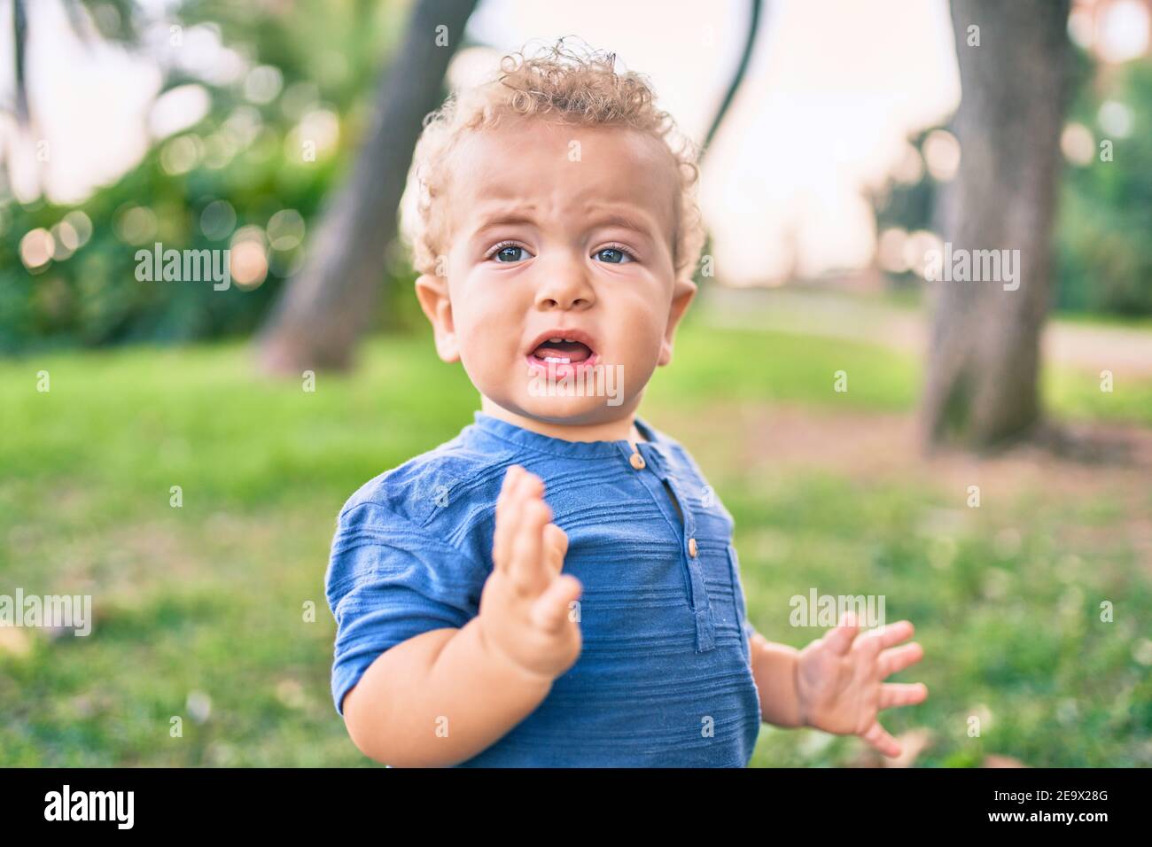Cute and sad little boy crying having a tantrum at the park on a sunny ...