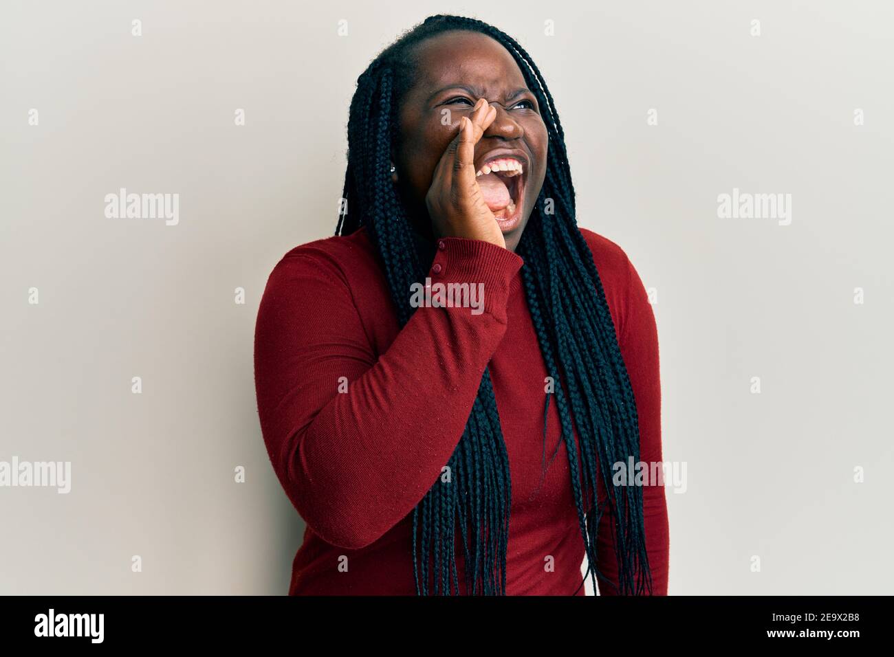 Young black woman with braids wearing casual clothes shouting and ...