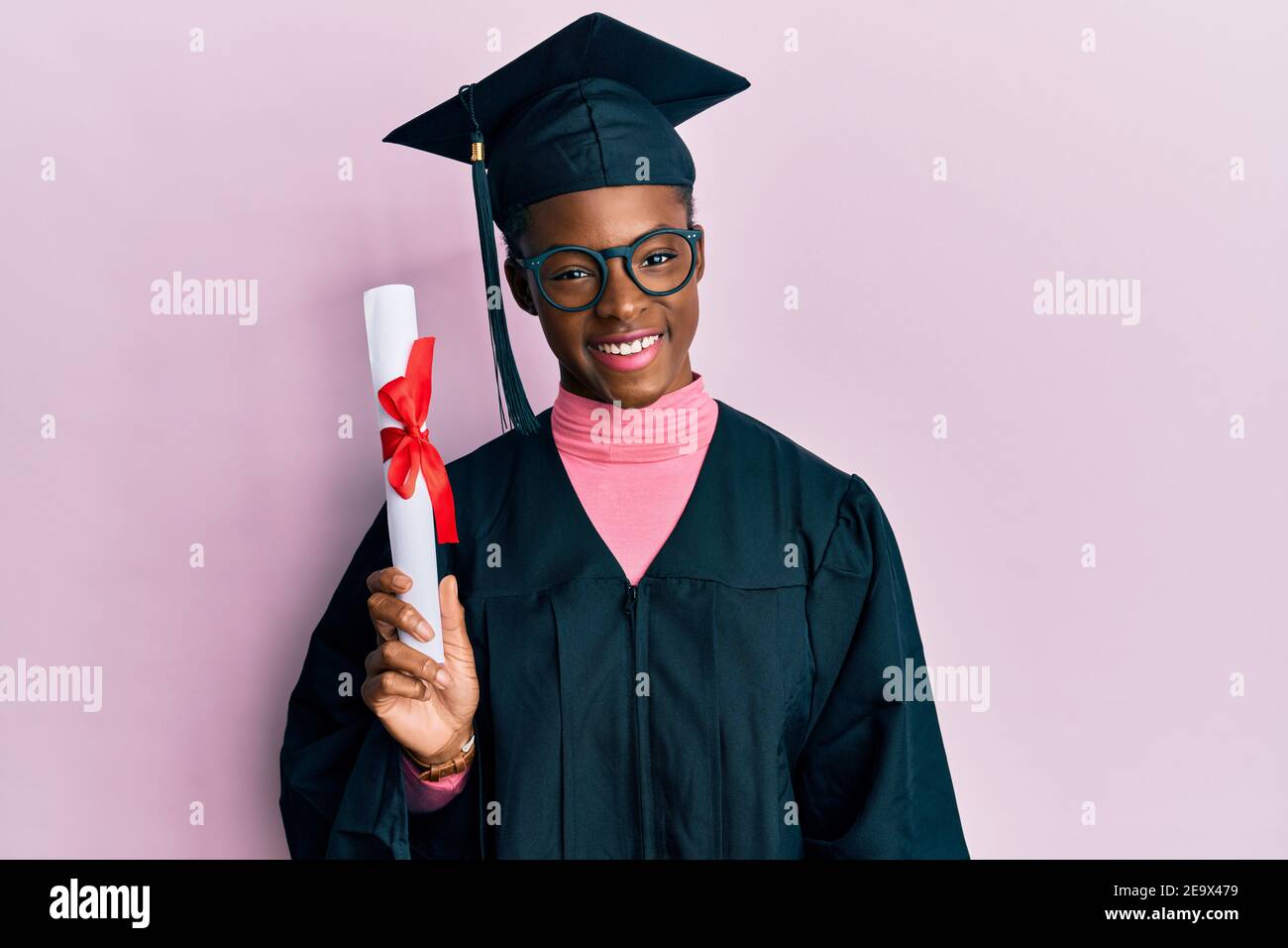 Young african american girl wearing graduation cap and ceremony robe ...