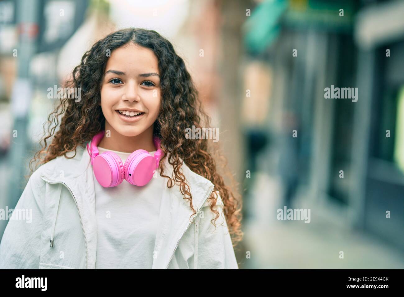 Hispanic child girl smiling happy using headphones at the city Stock ...