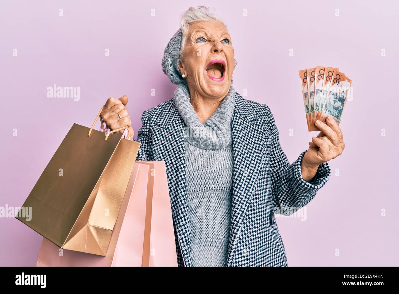 Senior grey-haired woman holding shopping bags and australia dollars ...