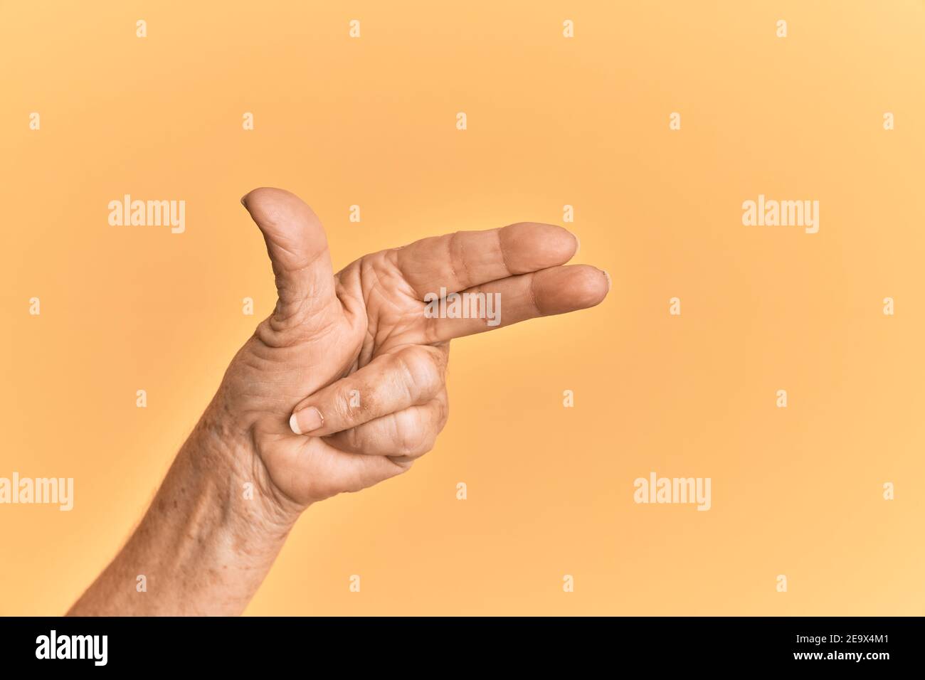 Senior caucasian hand over yellow isolated background gesturing fire ...