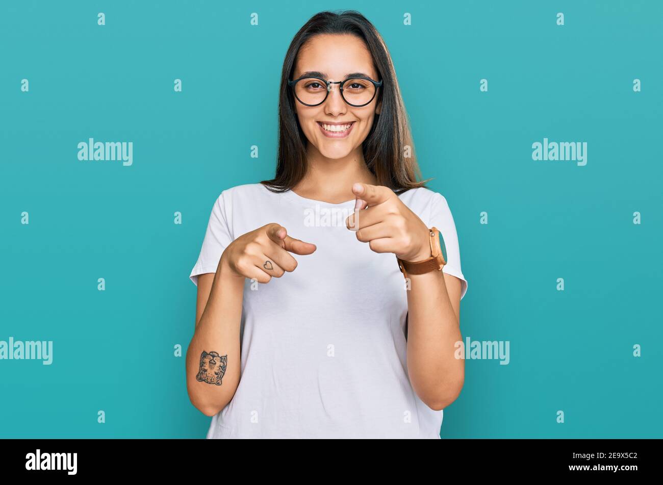 Young hispanic woman wearing casual white t shirt pointing fingers to ...