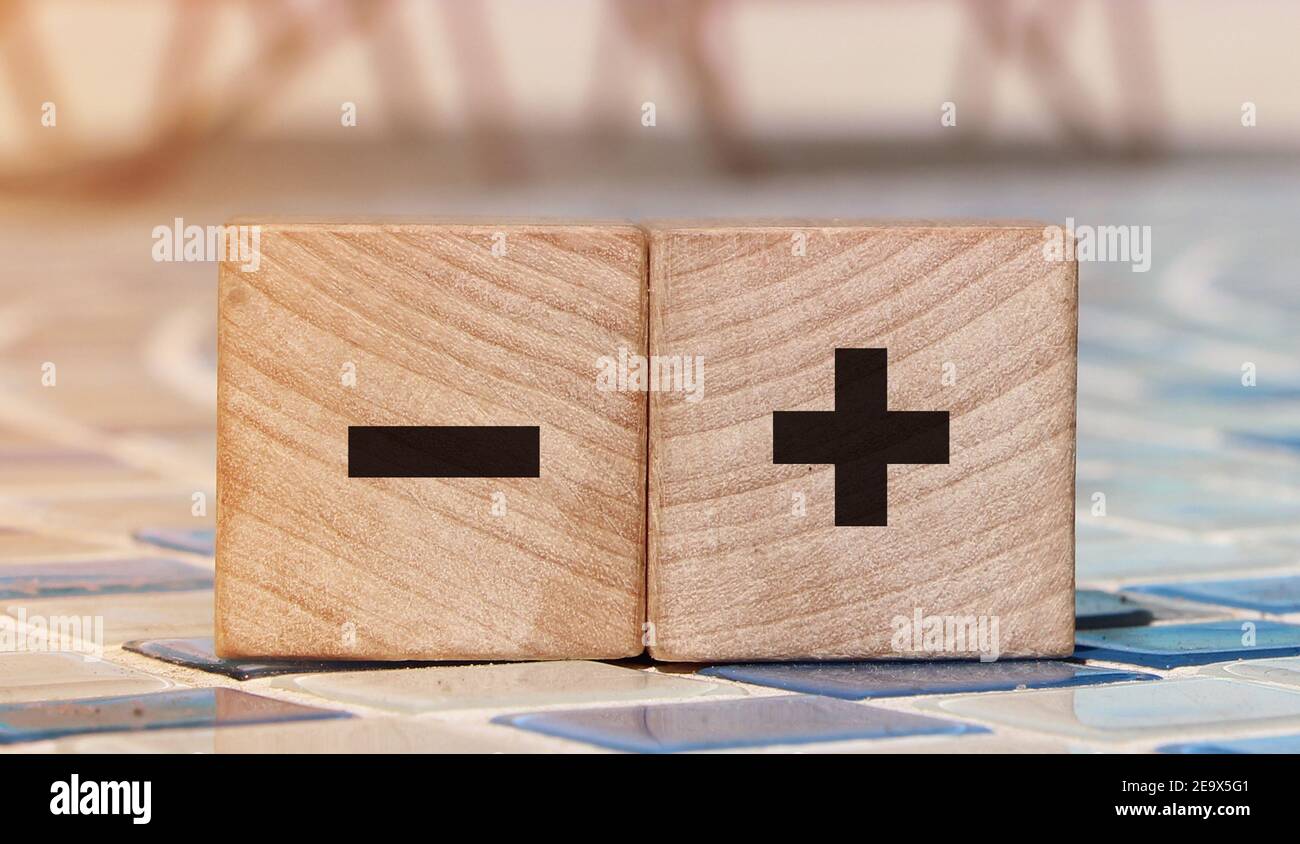 Plus and minus sign on wooden cubes on relaxed beach background ...