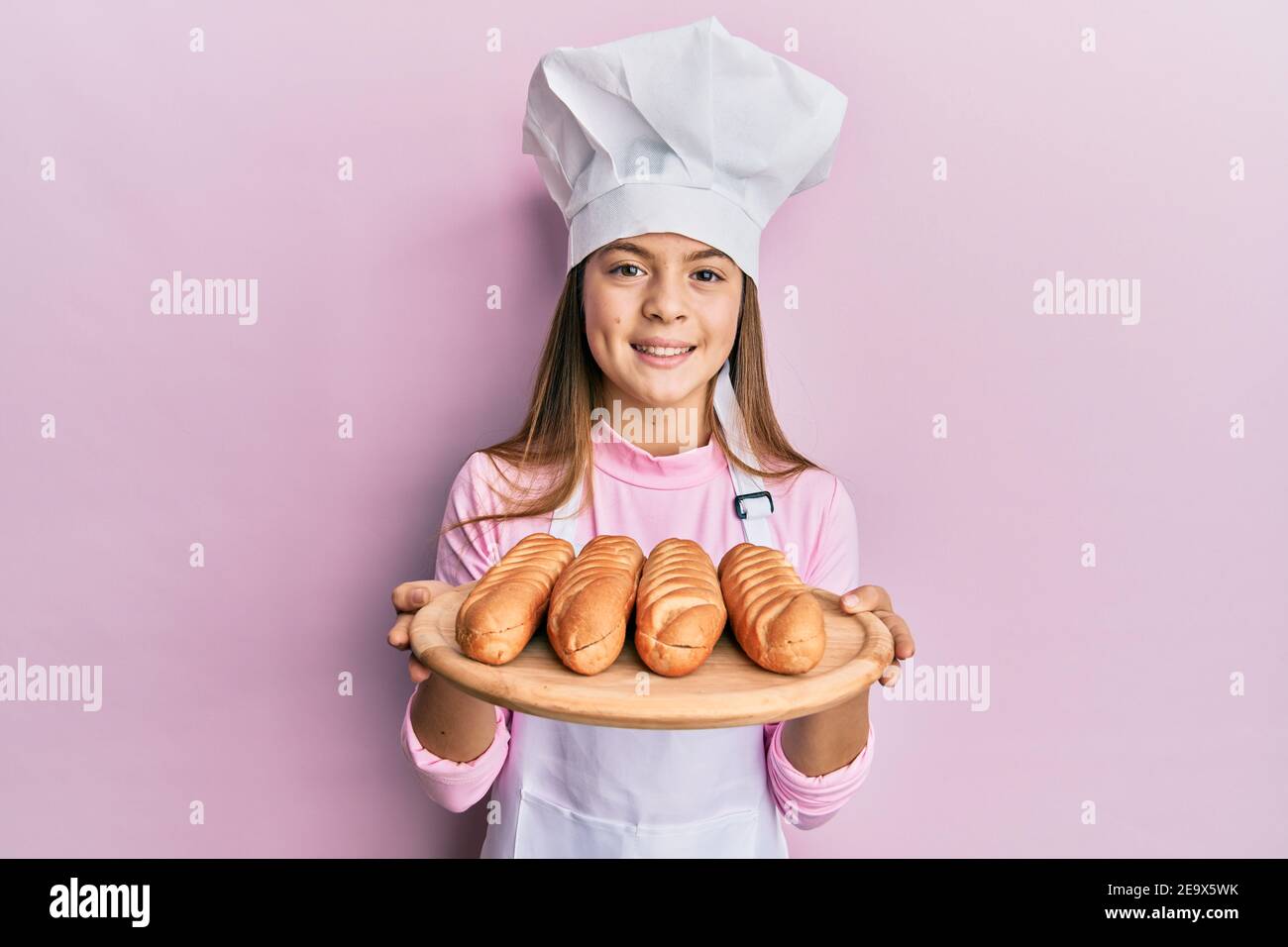 Beautiful brunette little girl wearing baker uniform holding homemade ...