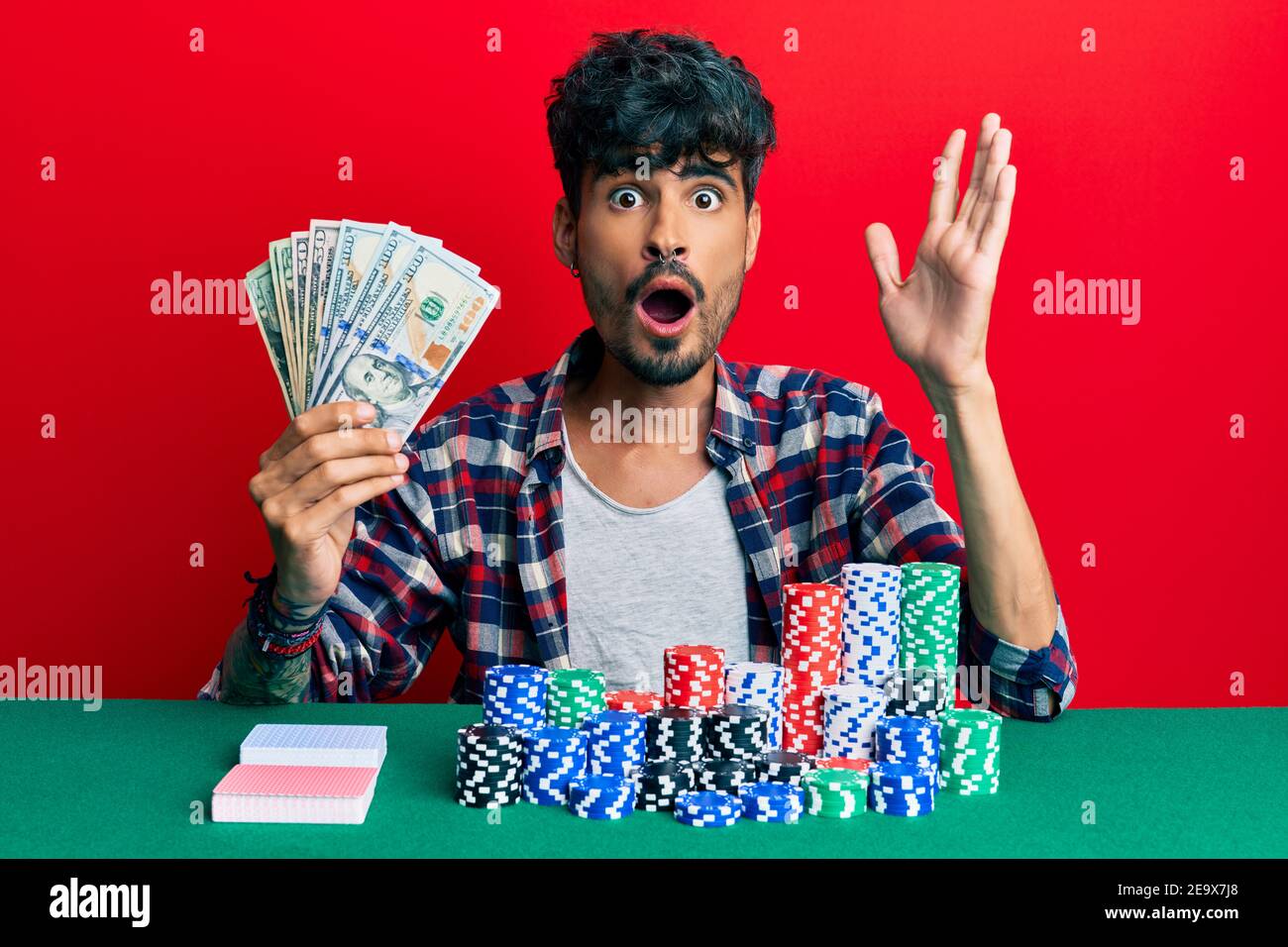 Young hispanic man sitting on the table with poker chips and cards ...