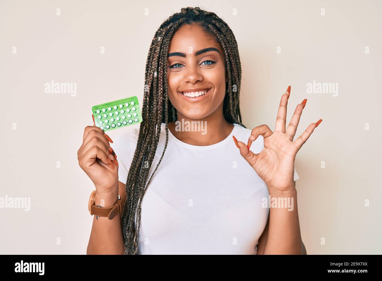 Young african american woman with braids holding birth control pills ...