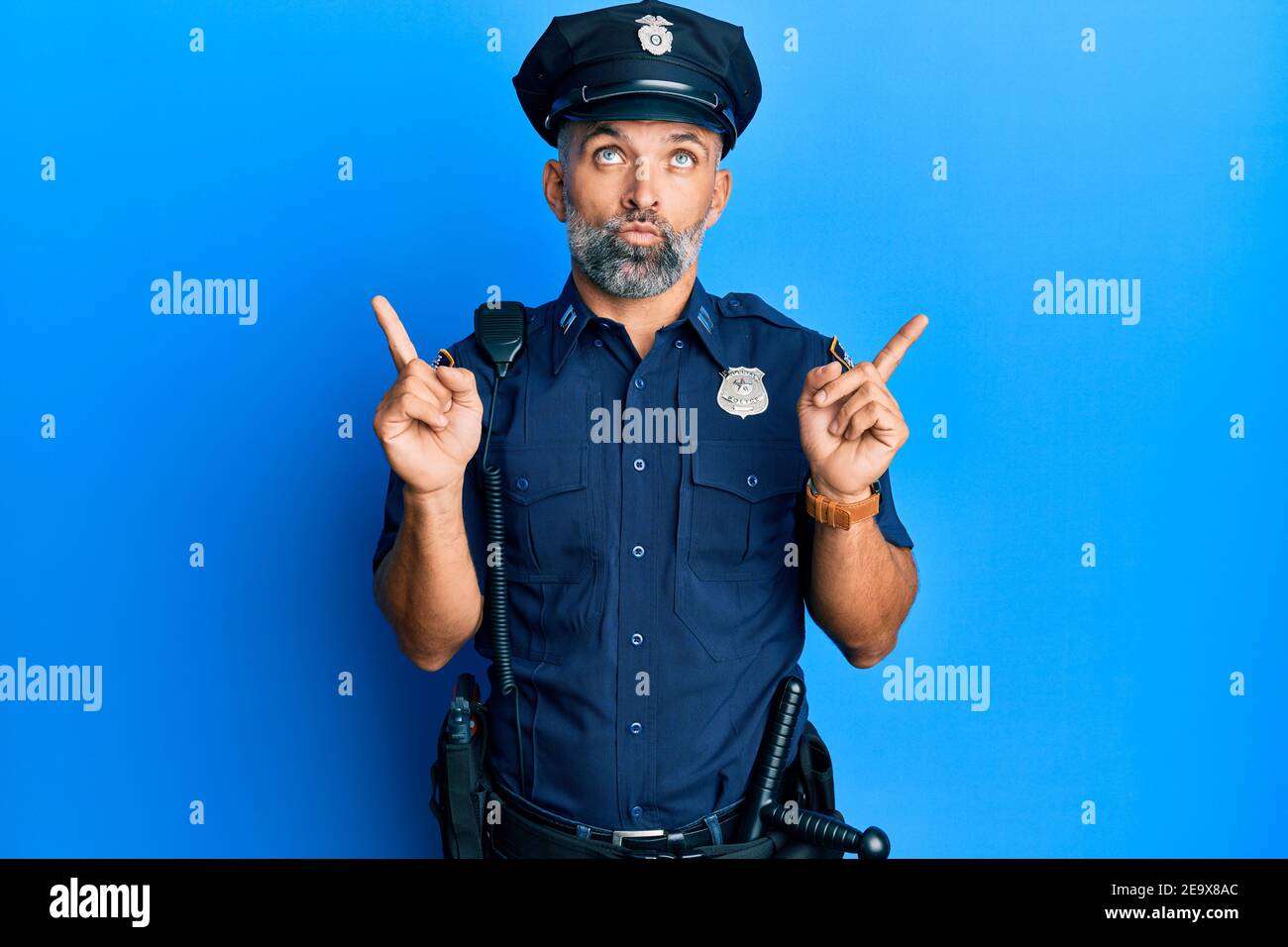 Middle age handsome man wearing police uniform pointing up looking sad ...