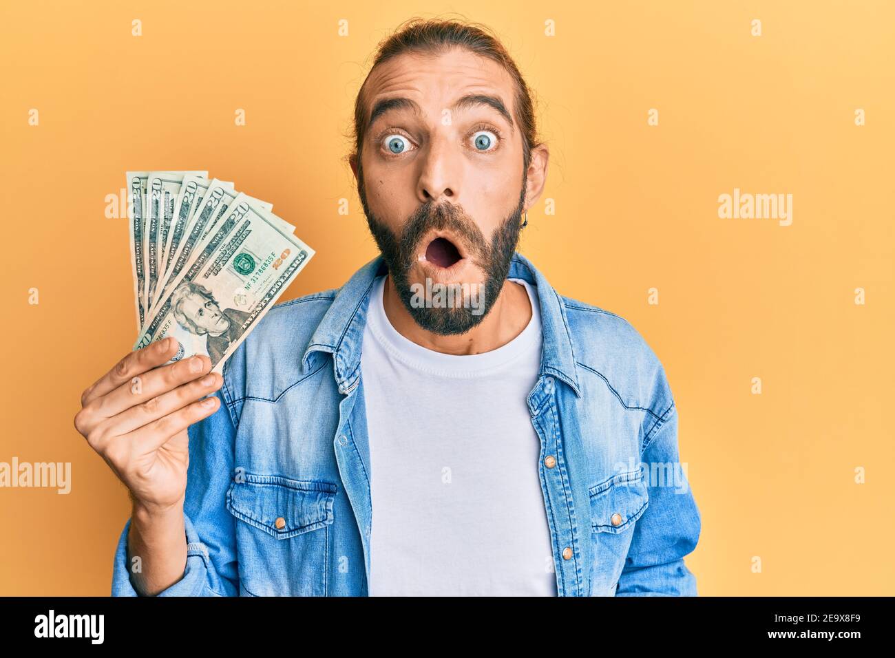 Attractive man with long hair and beard holding 20 dollars banknote ...