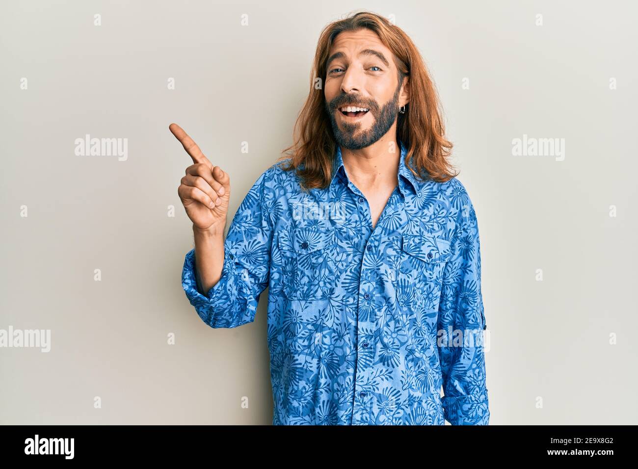 Attractive man with long hair and beard wearing 80s disco style shirt ...
