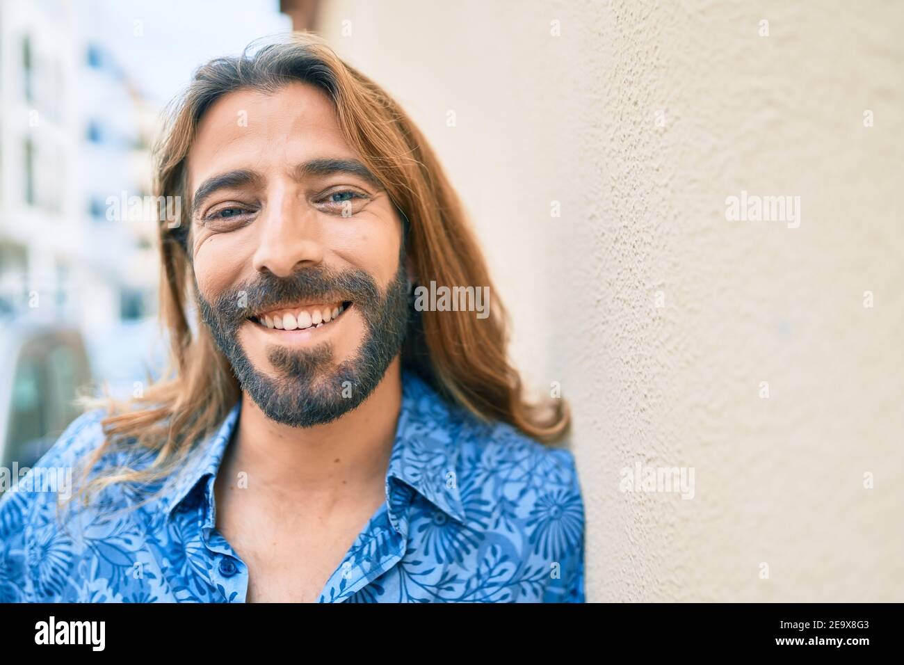 Young middle eastern man smiling happy leaning on the wall at the city ...