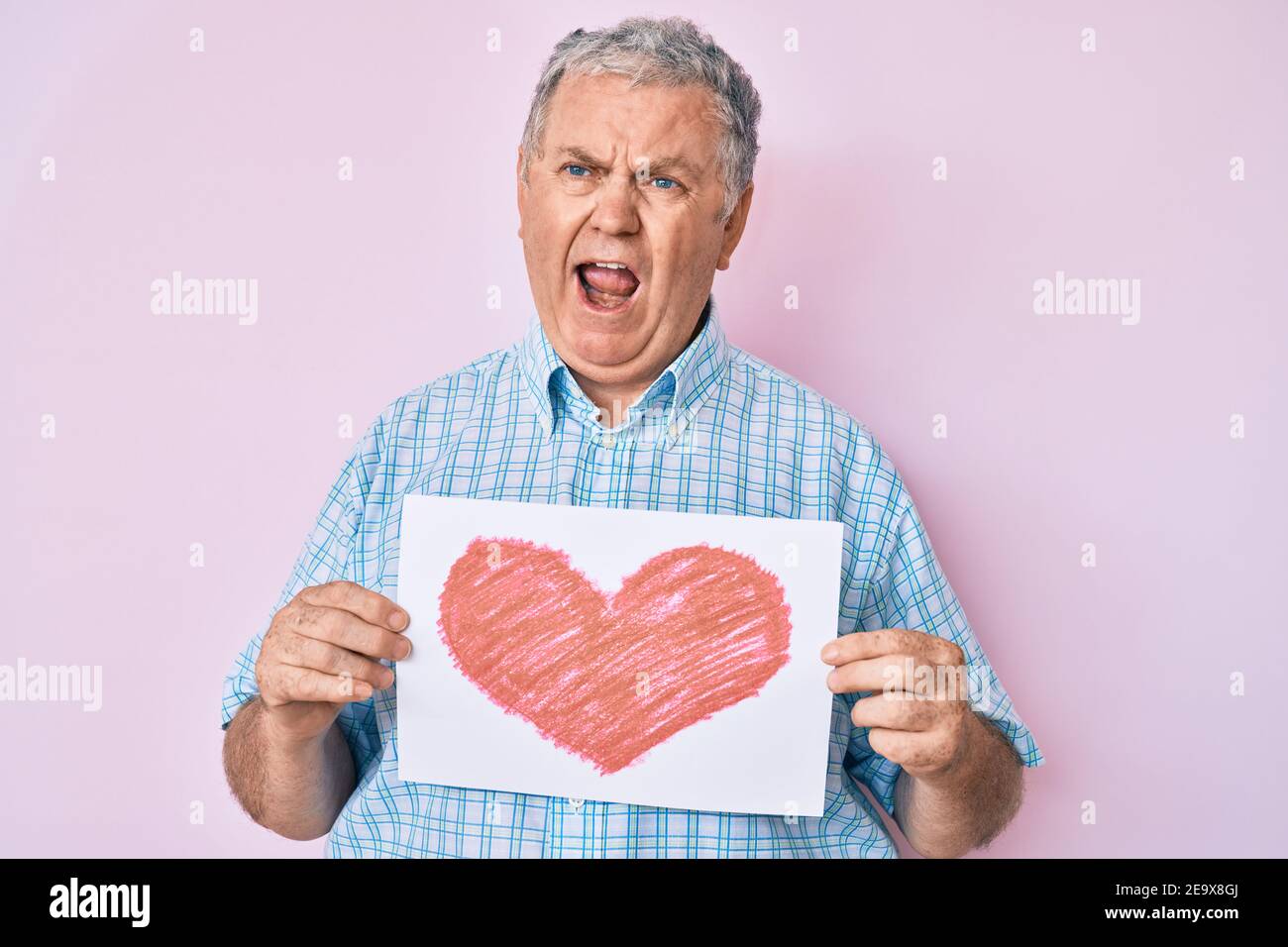 Senior grey-haired man holding heart draw angry and mad screaming ...
