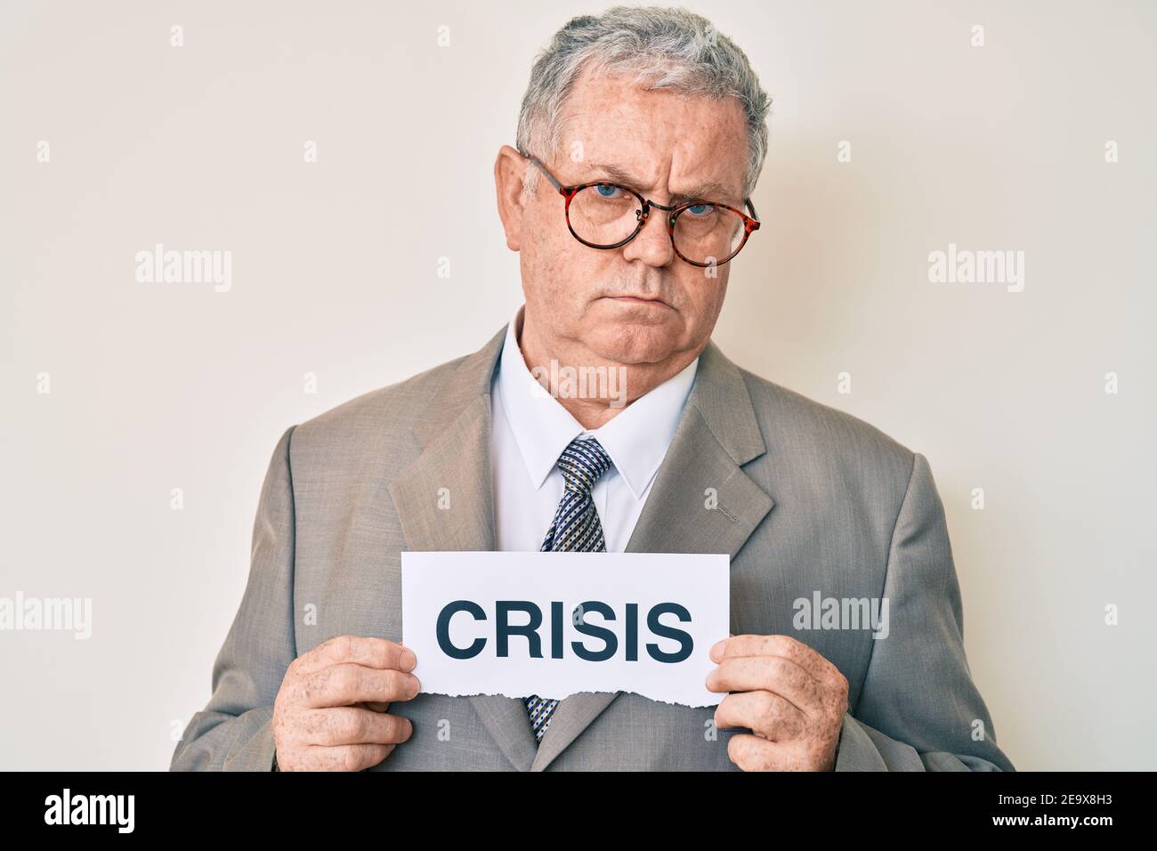 Senior grey-haired man wearing business suit holding crisis paper ...
