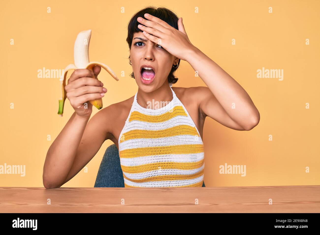 Brunette teenager girl eating banana as healthy snack stressed and ...