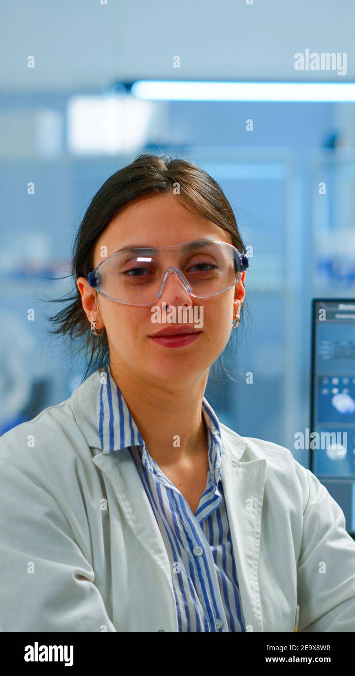 Chemist with lab coat sitting in laboratory looking at camera smiling ...