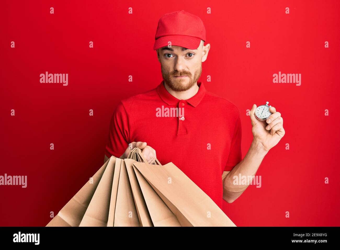Young redhead man holding delivery bags and countdown clock clueless ...