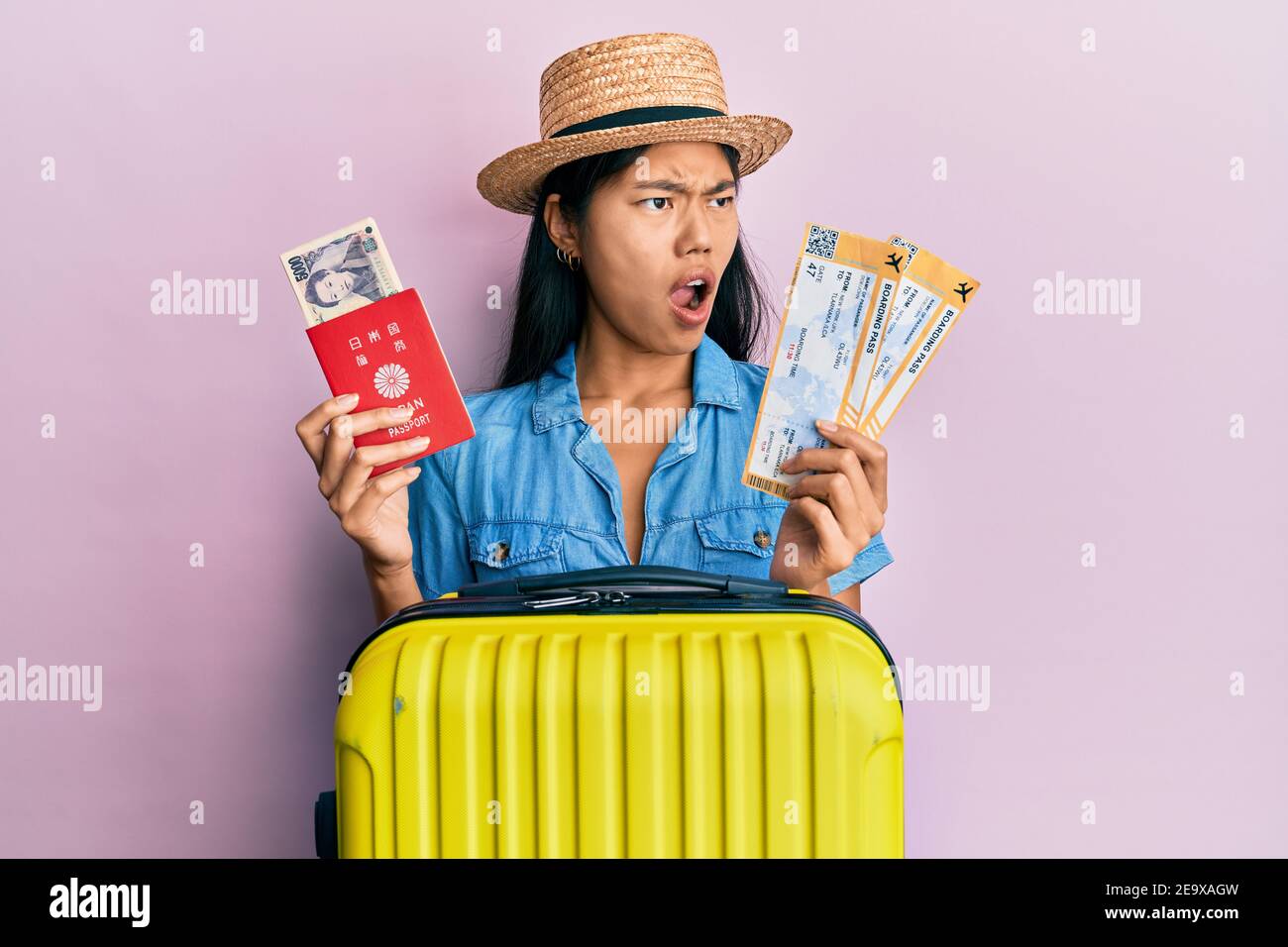 Young chinese woman holding boarding pass and passport angry and mad ...
