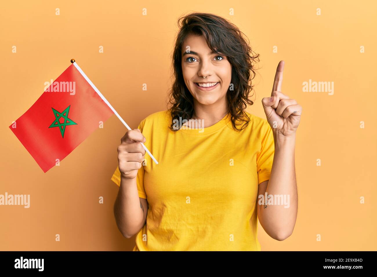 Young hispanic woman holding morocco flag smiling with an idea or ...