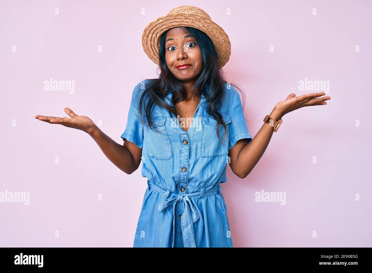 Young indian girl wearing summer hat clueless and confused with open ...