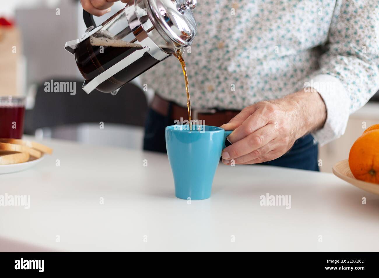 Older man spilling coffee in cup after making it using french press for ...